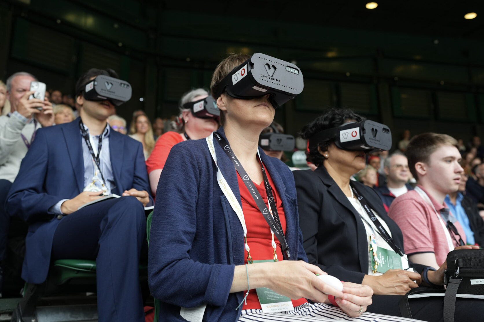 Visually impaired tennis fans, in their seats at Wimbledon, wearing GiveVision headsets powered ...